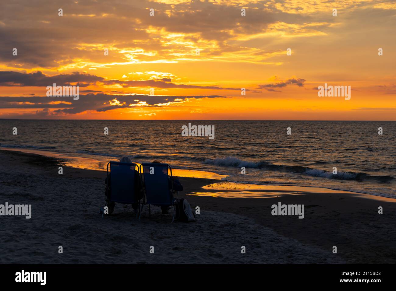 Elder couple resting on the beach during beatiful sunset. Dramatic ...