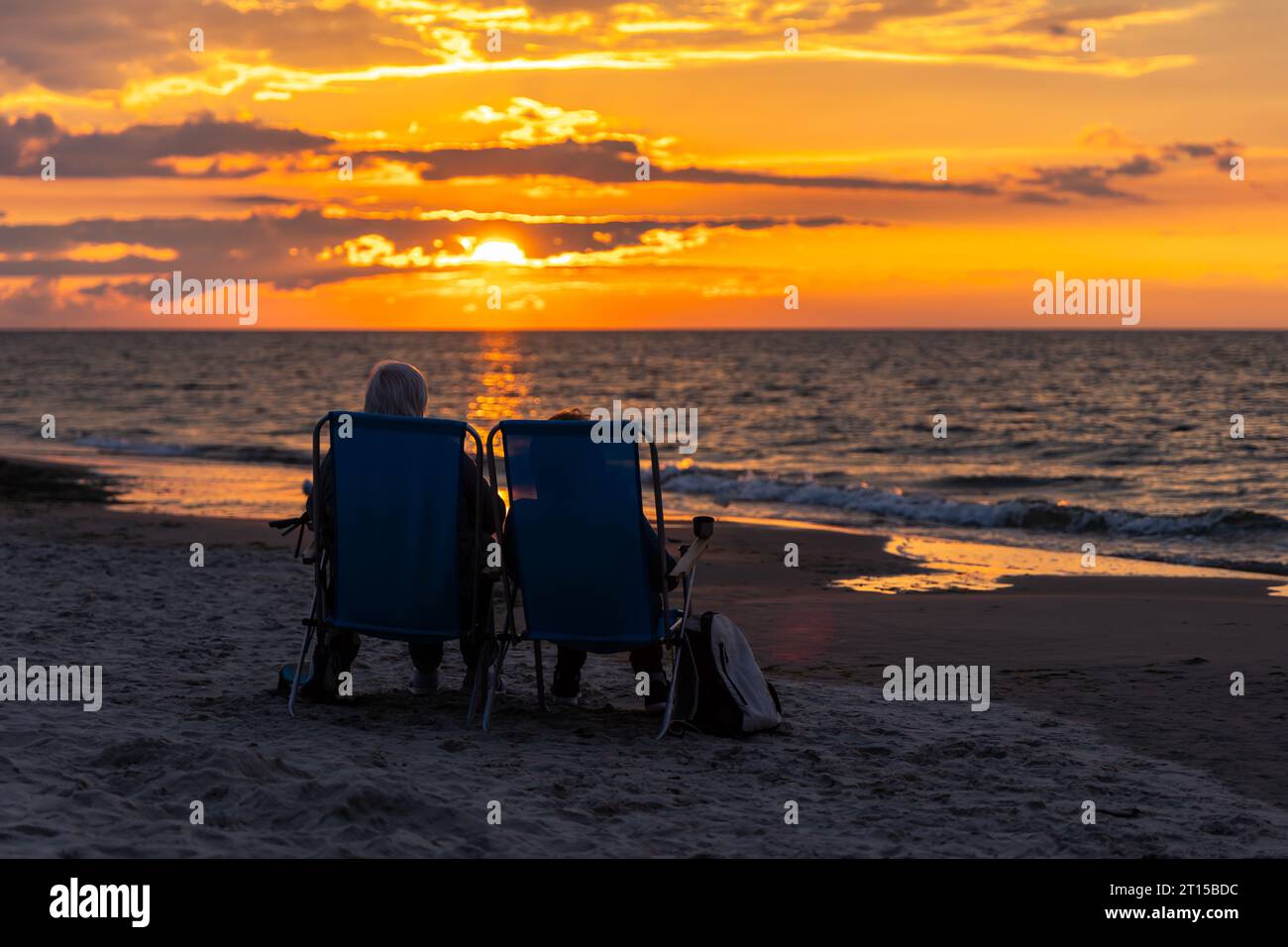 Elder couple resting on the beach during beatiful sunset. Dramatic ...