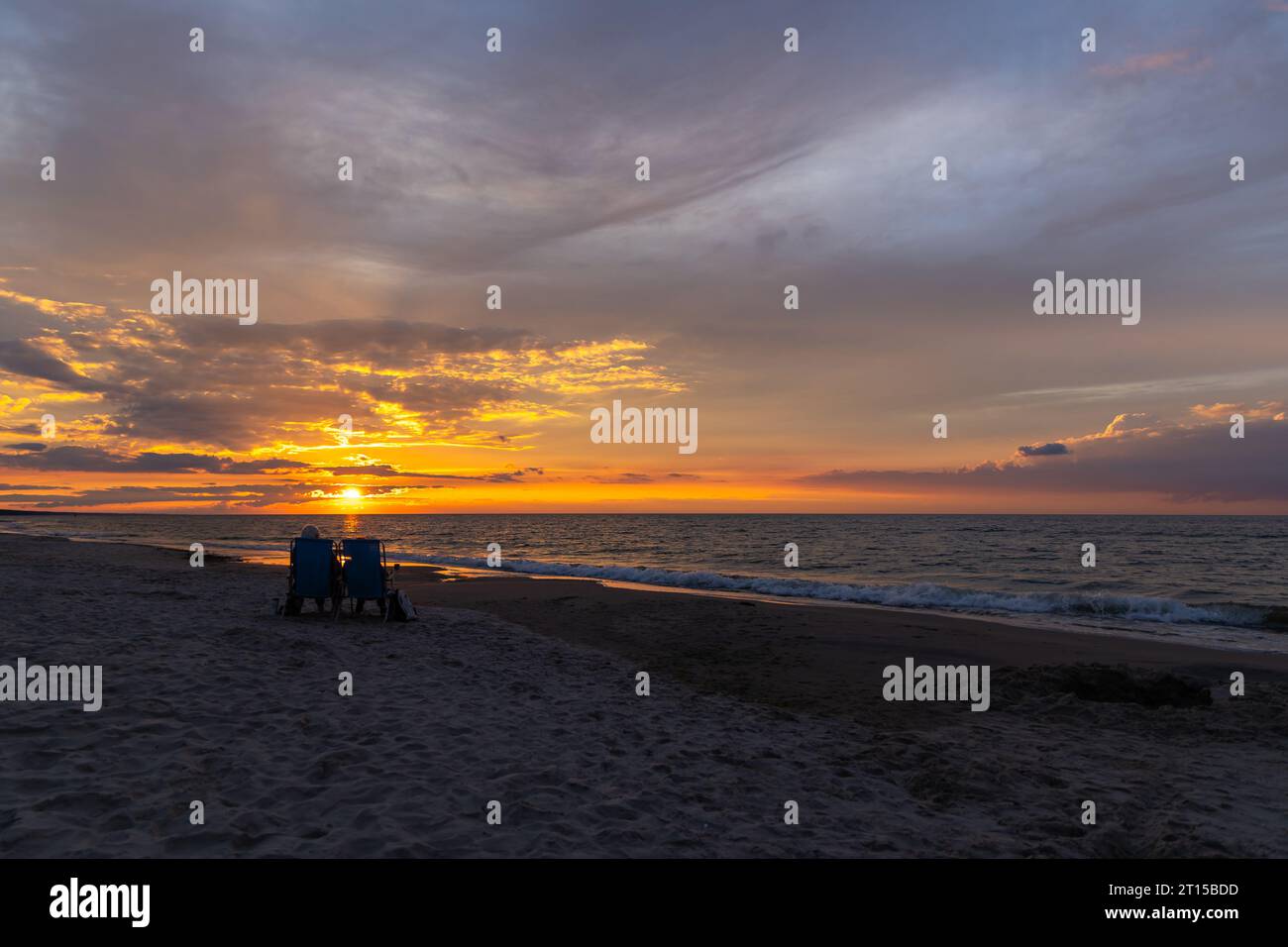 Elder couple resting on the beach during beatiful sunset. Dramatic ...