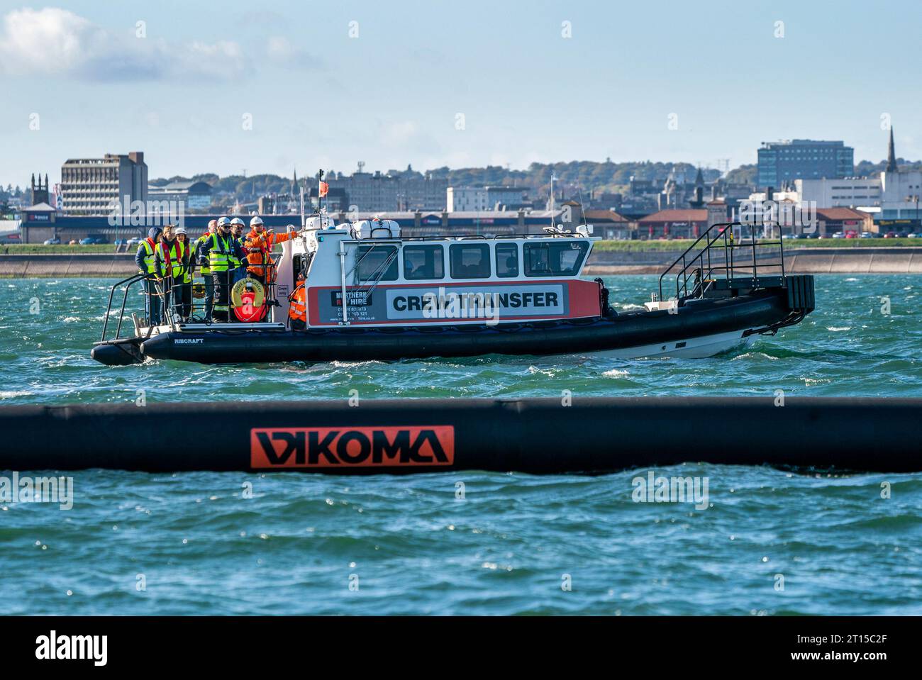 Personnel on a support boat observing a heavy duty ocean boom being ...