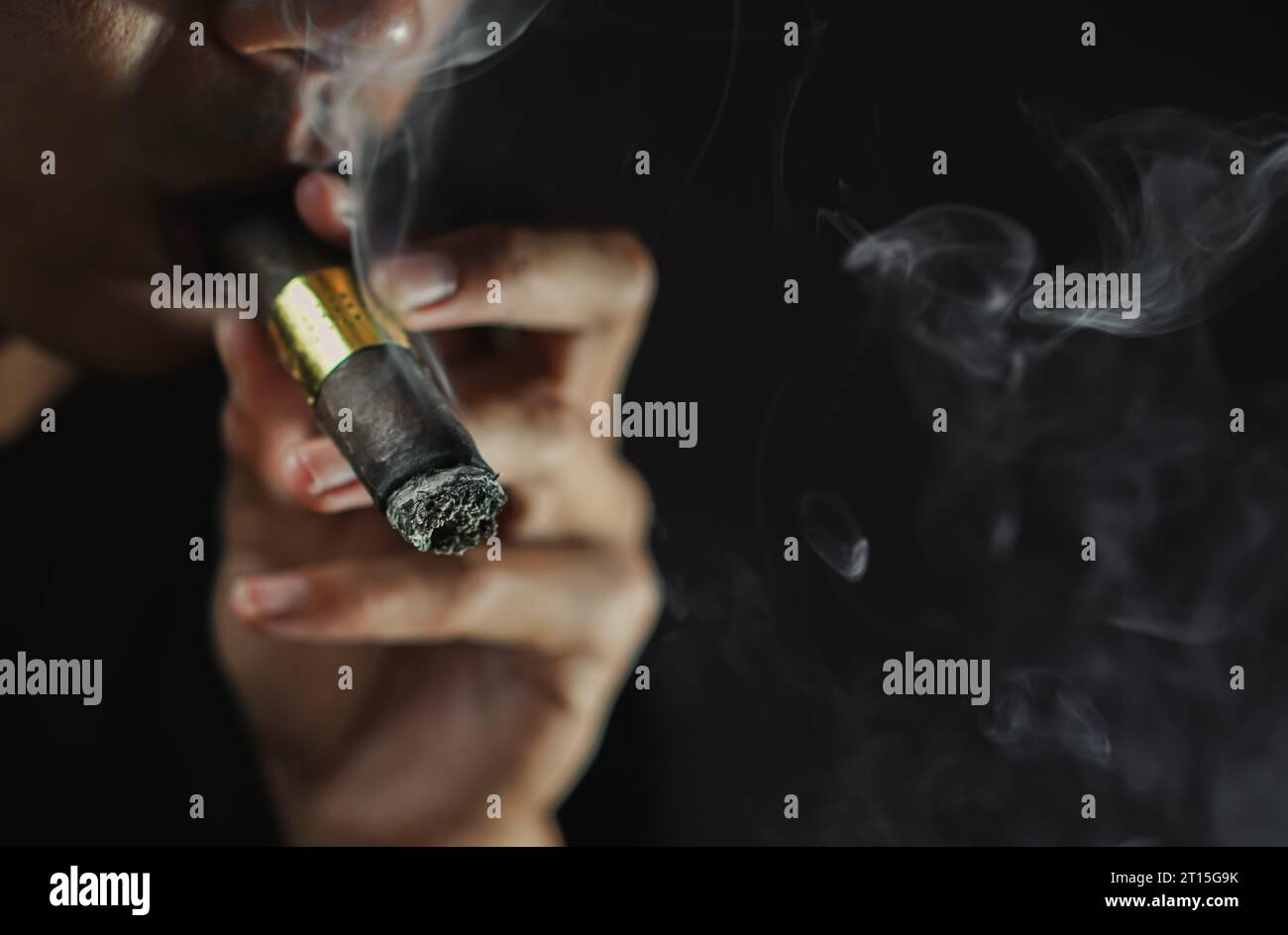 A man smoking cigar in dark room Stock Photo - Alamy