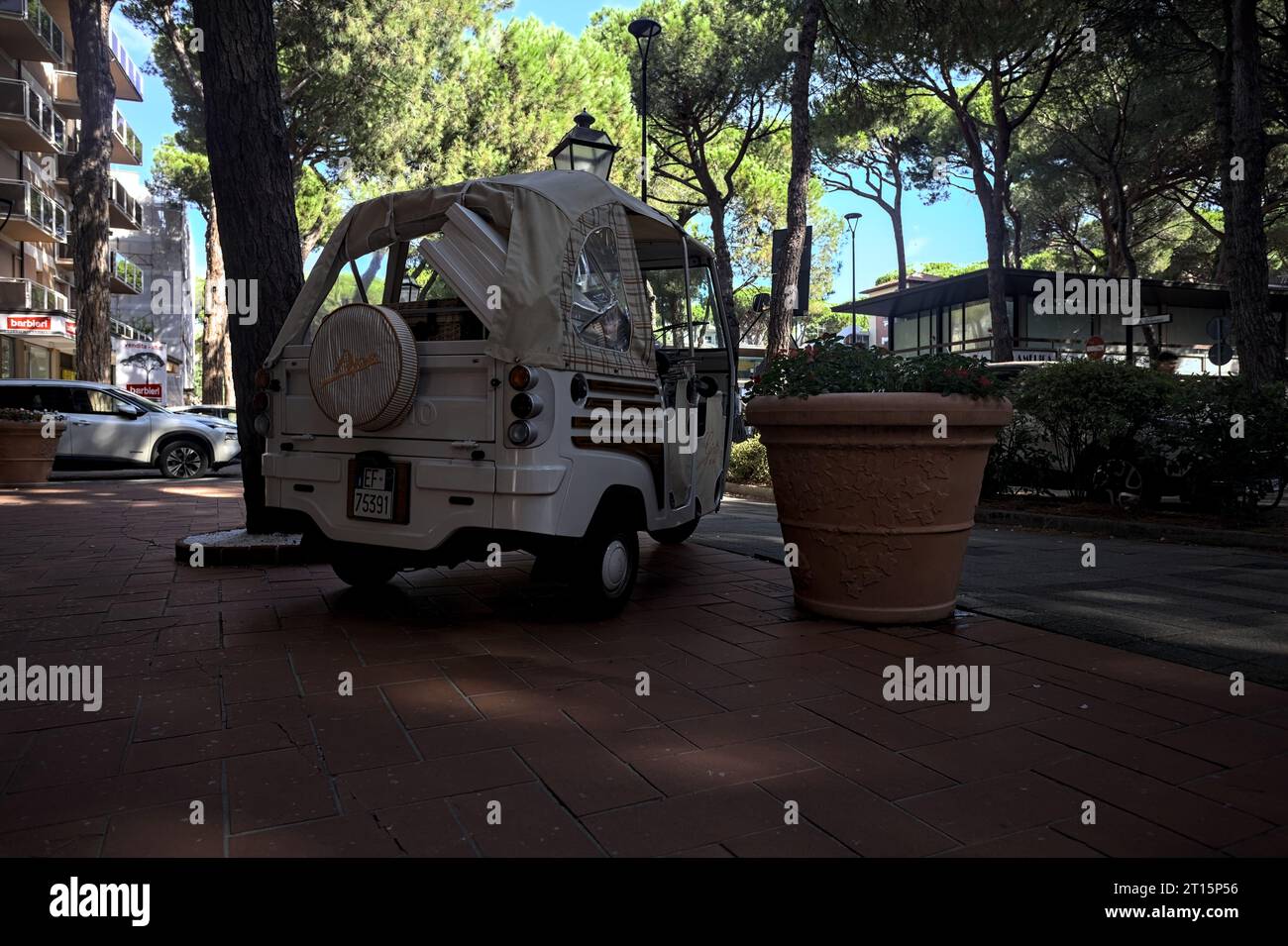 White Piaggio Ape Calessino on the pavement next to shop windows in an ...