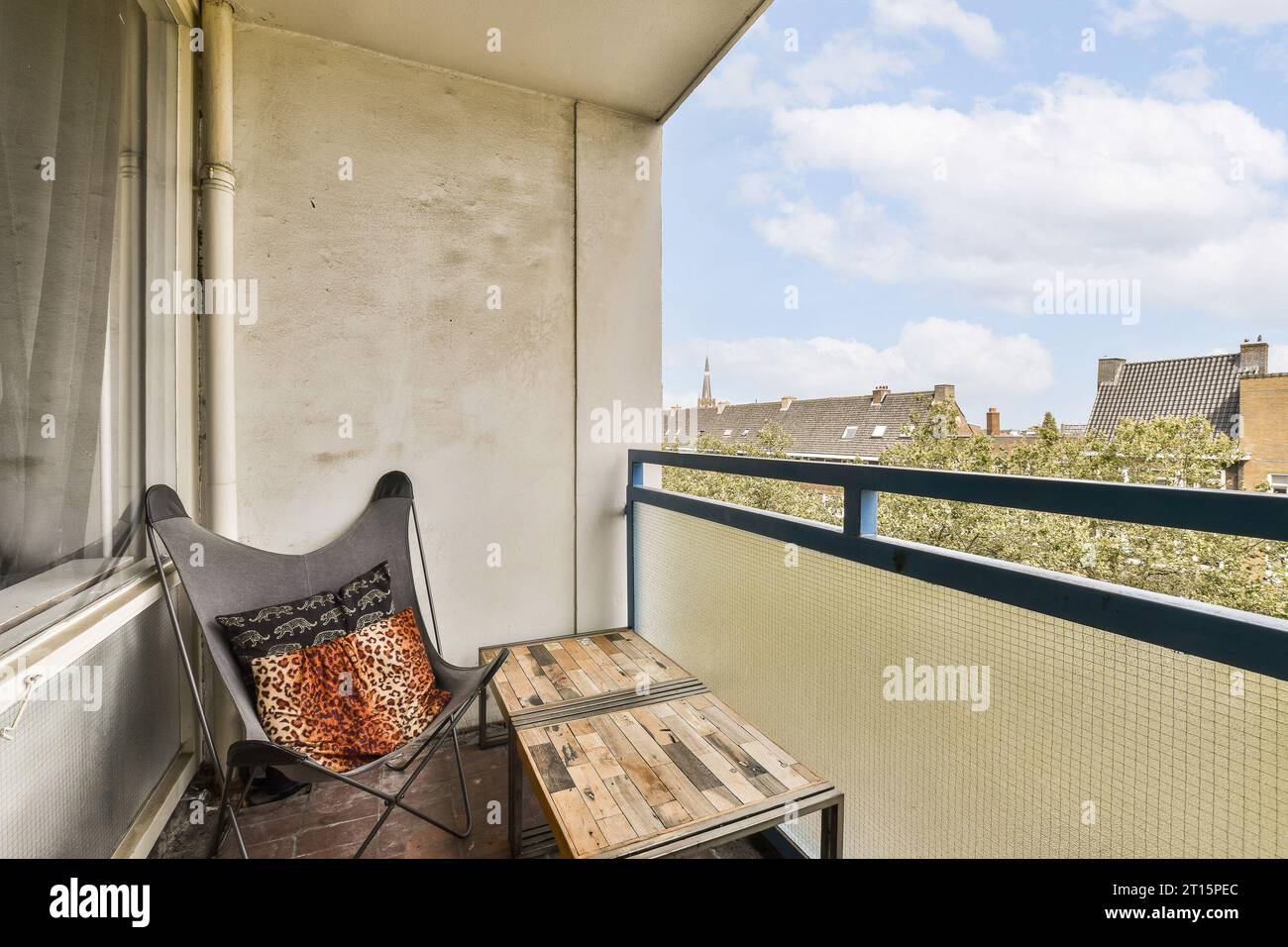 a balcony with a chair and table on the left side, looking out to the ...