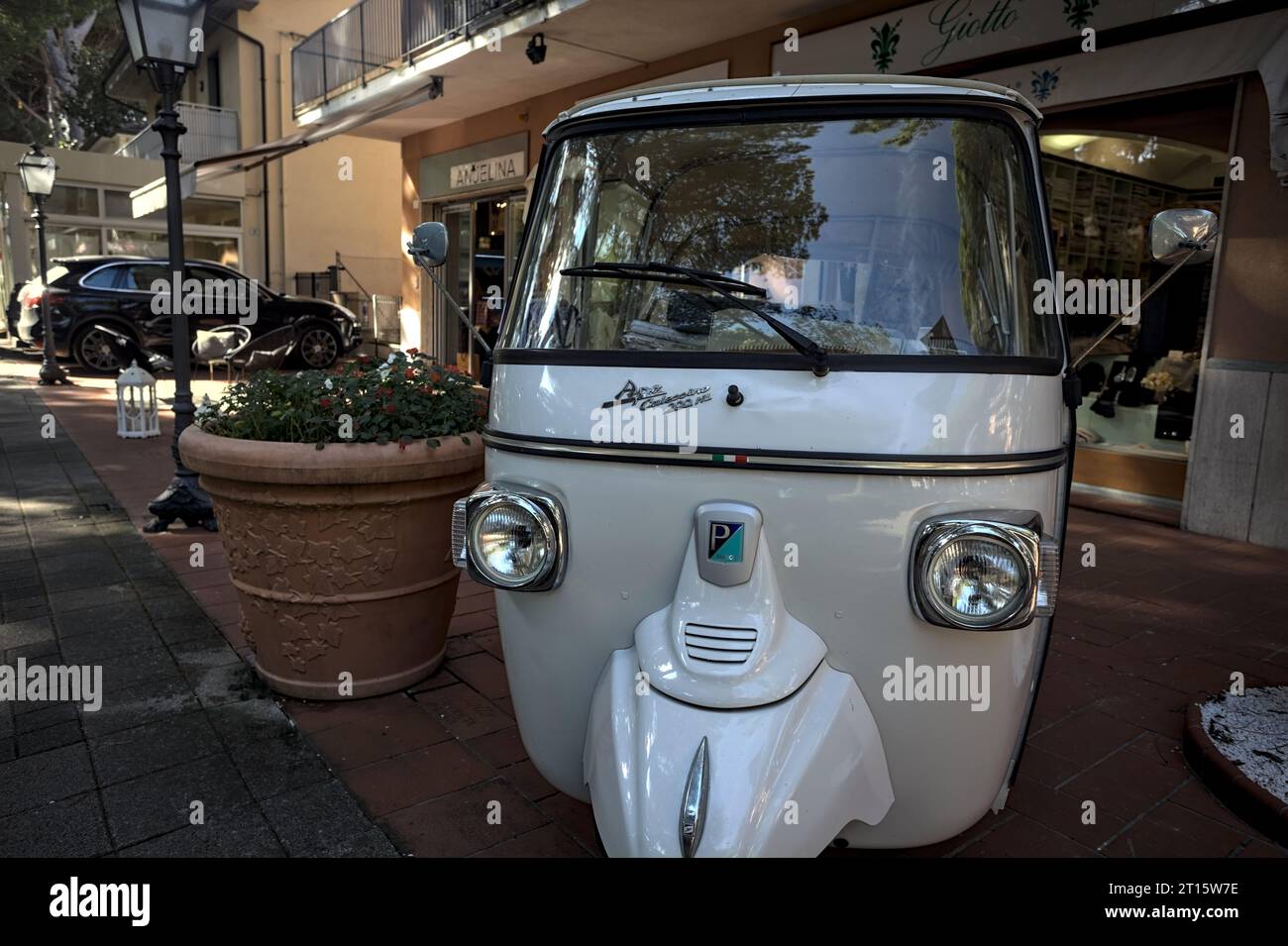 White Piaggio Ape Calessino on the pavement next to shop windows in an ...
