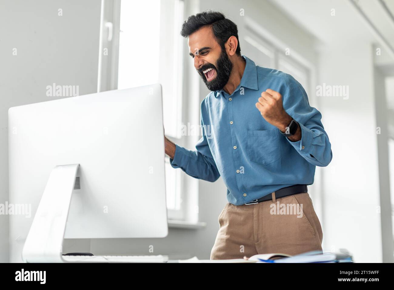 Business success. Overjoyed indian businessman shaking fists while ...