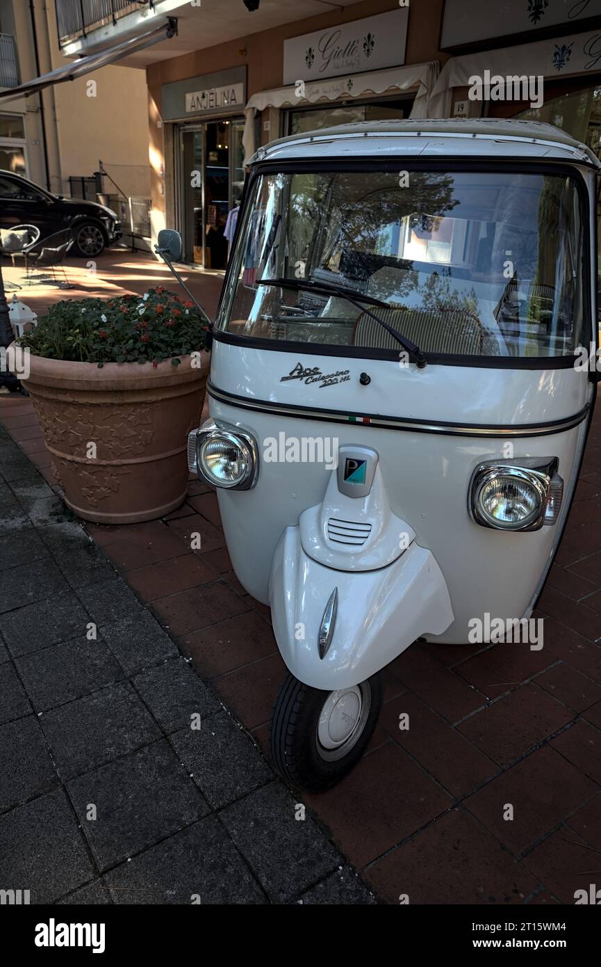 White Piaggio Ape Calessino on the pavement next to shop windows in an ...