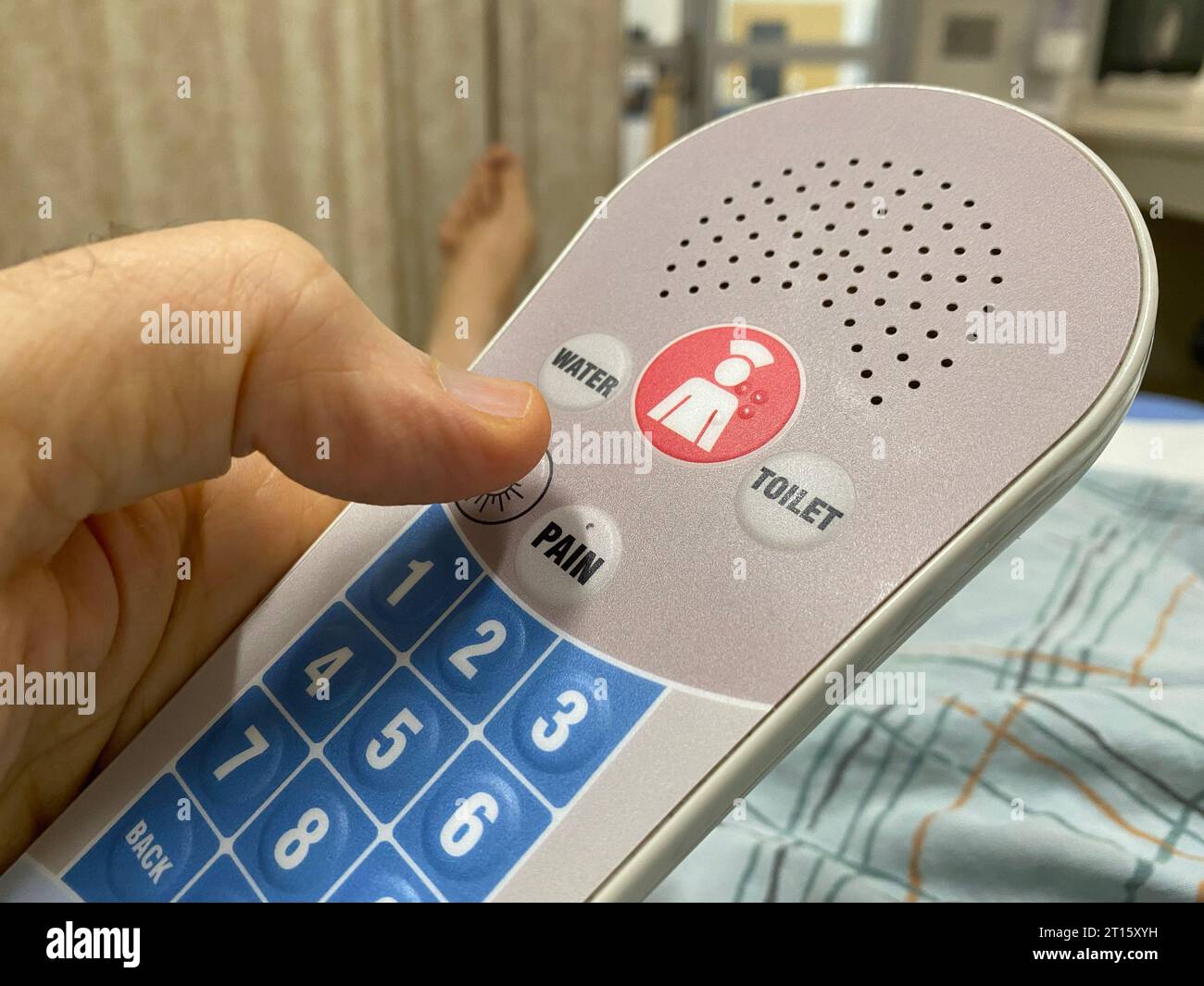 Close-up of male patient using remote in hospital bed with nurse, water ...