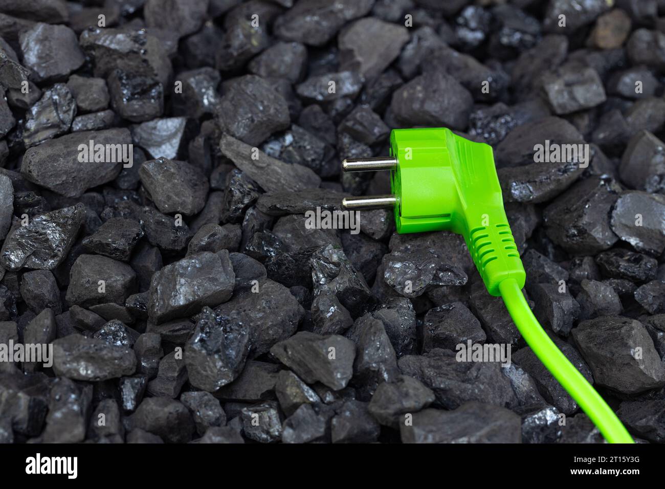 green plug lying on black coal, Environmental concept, renewable energy ...