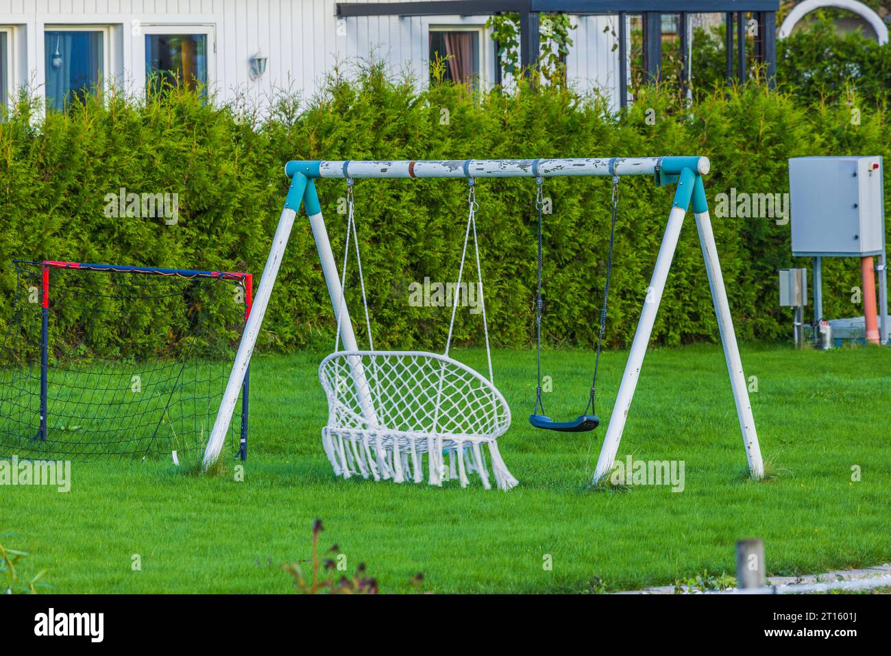 Green playground with swings and football goals on white villa ...