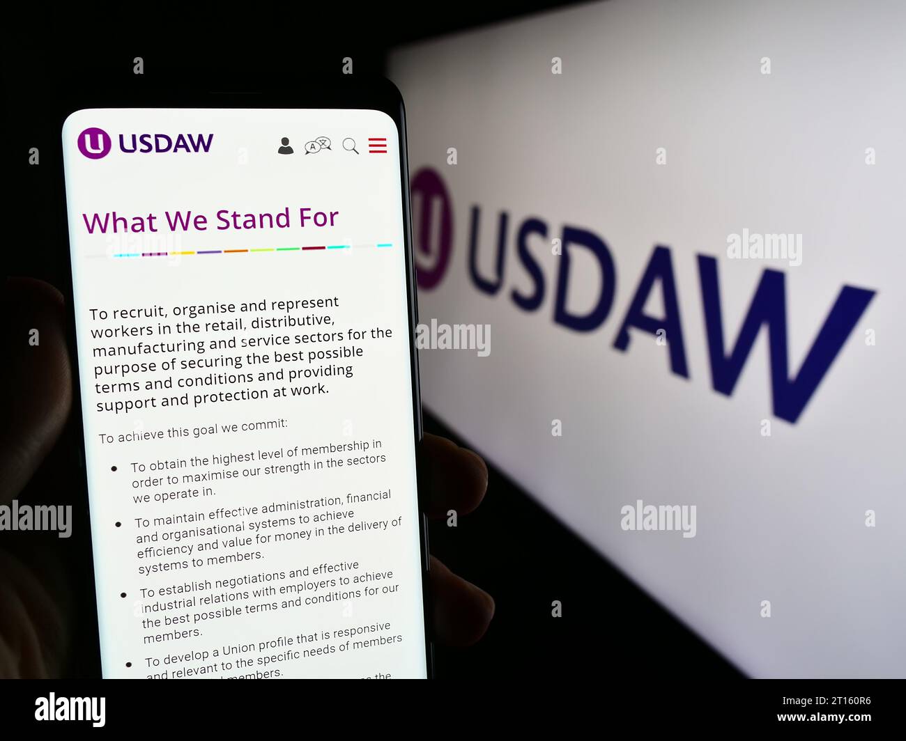 Person holding mobile phone with web page of Union of Shop Distributive ...