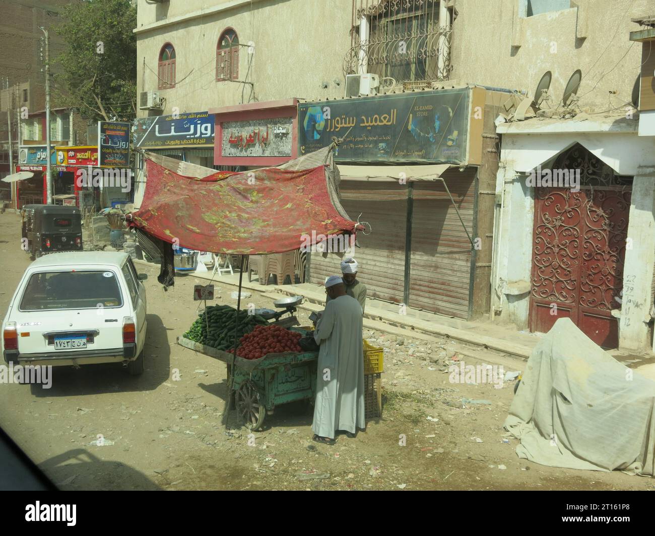 Egyptian men in traditional gallibaya at a roadside market stall with a ...