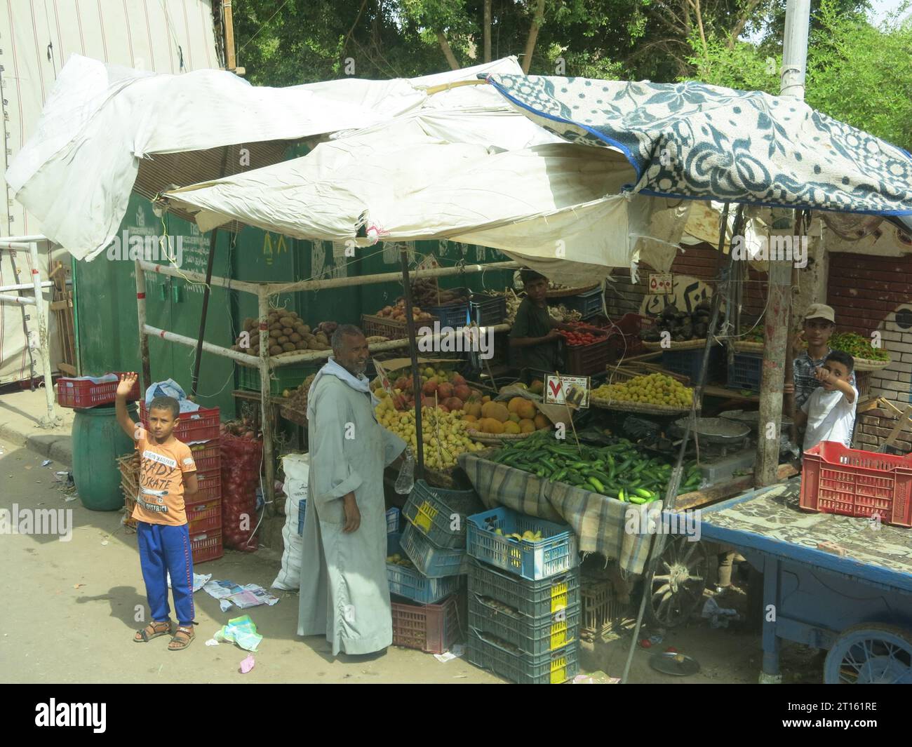 An Egyptian man and young child at a roadside stall selling fruit and ...