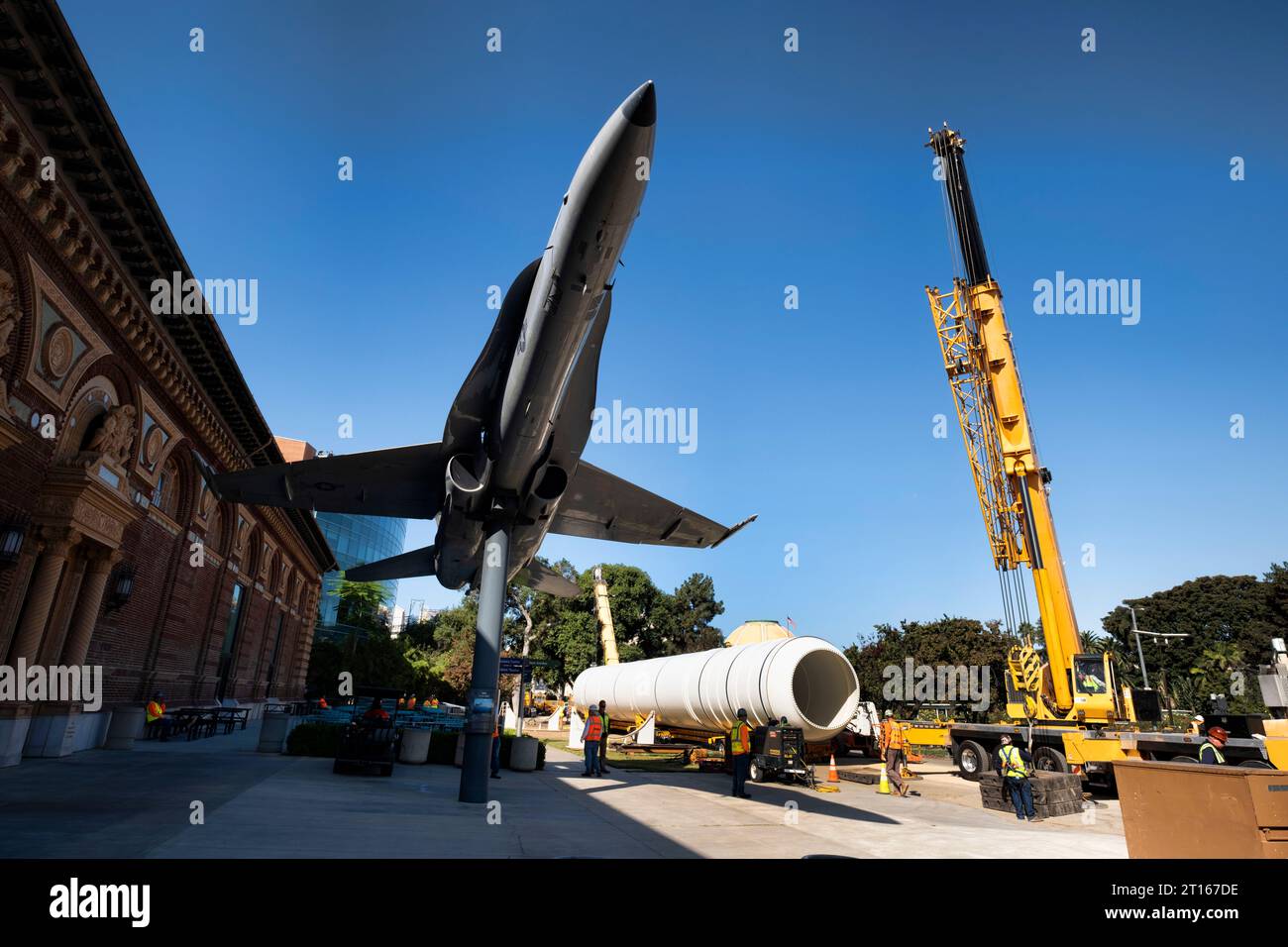 One of two rocket motors are temporarily placed next to an F-18 fighter ...