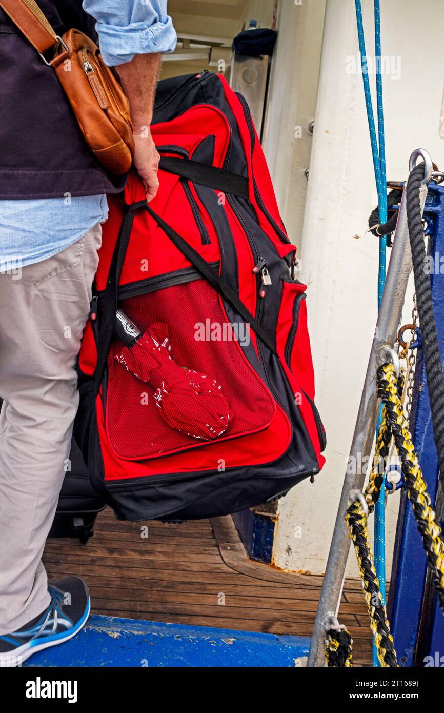 passenger holds a red backpack before loading onto the liner. Refugees ...