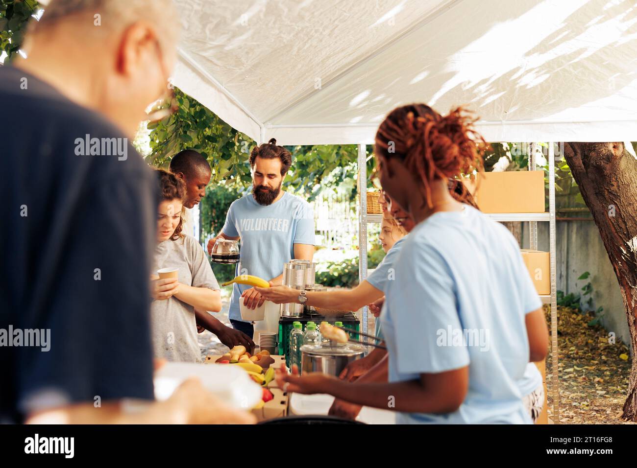 On sunny day, group of volunteers at local food bank handing out free ...