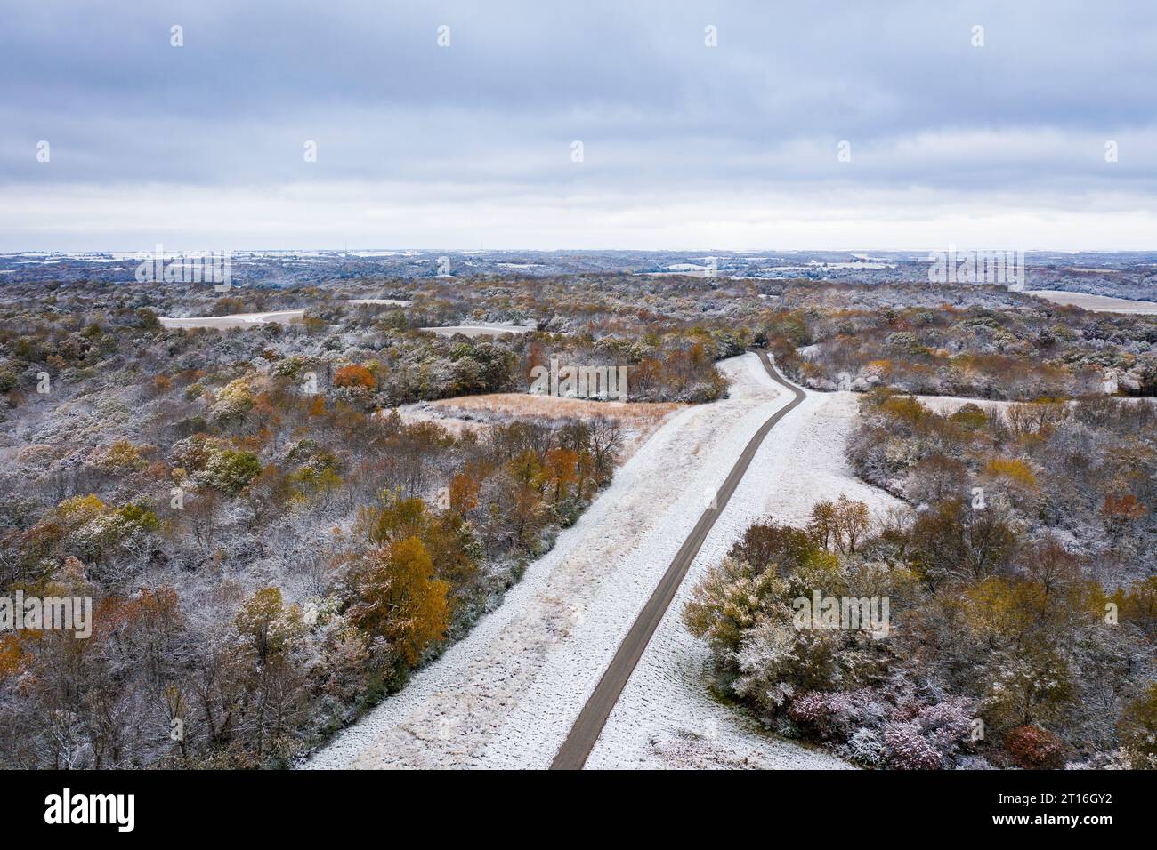 Gravel road, forest and harvested corn field dusted by early snow ...