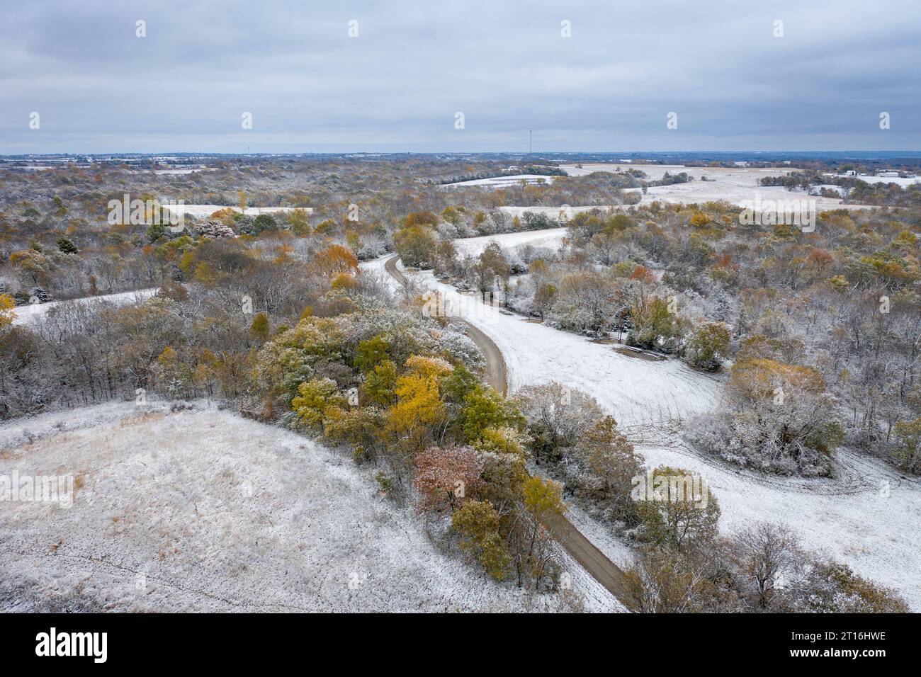 Gravel road, forest and harvested corn field dusted by early snow ...