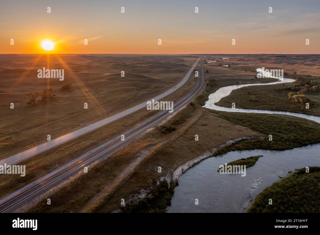 sunrise over a river meandering through Nebraska Sandhills, highway and ...