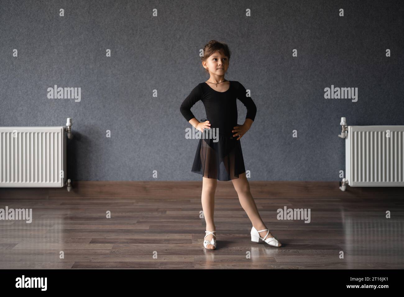 Child girl standing in black sport bodysuit in dancing studio during ...