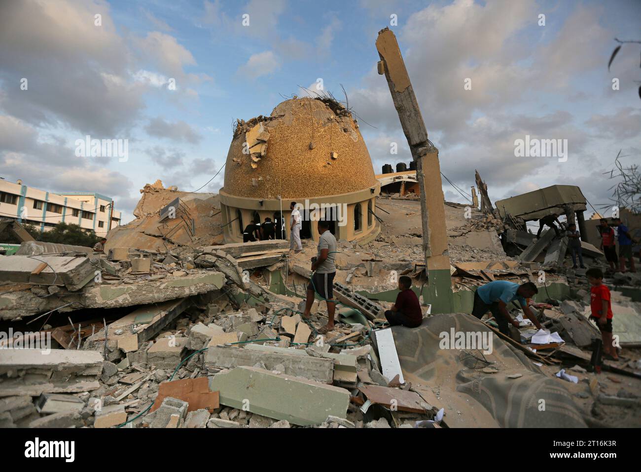 FILE - People stand outside a mosque destroyed in an Israeli air strike ...