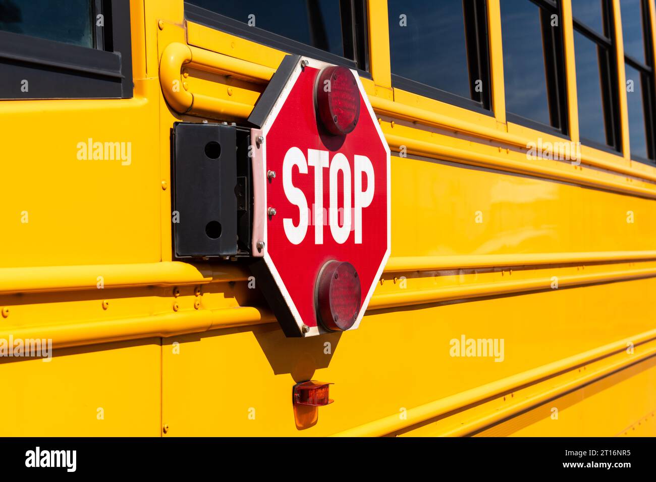 A big red stop sign on the side of a yellow school bus Stock Photo - Alamy