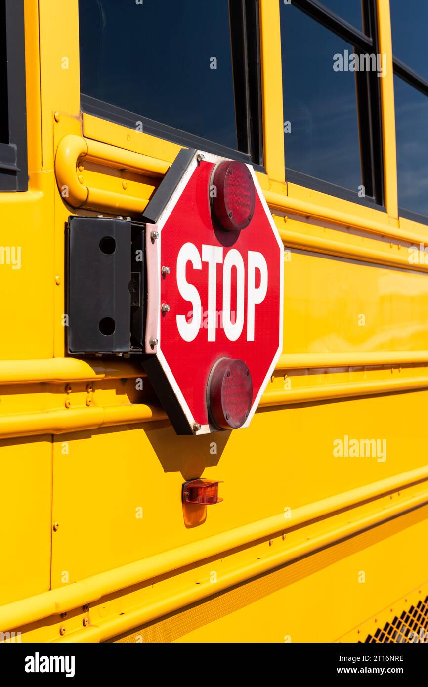 A big red stop sign on the side of a yellow school bus Stock Photo - Alamy