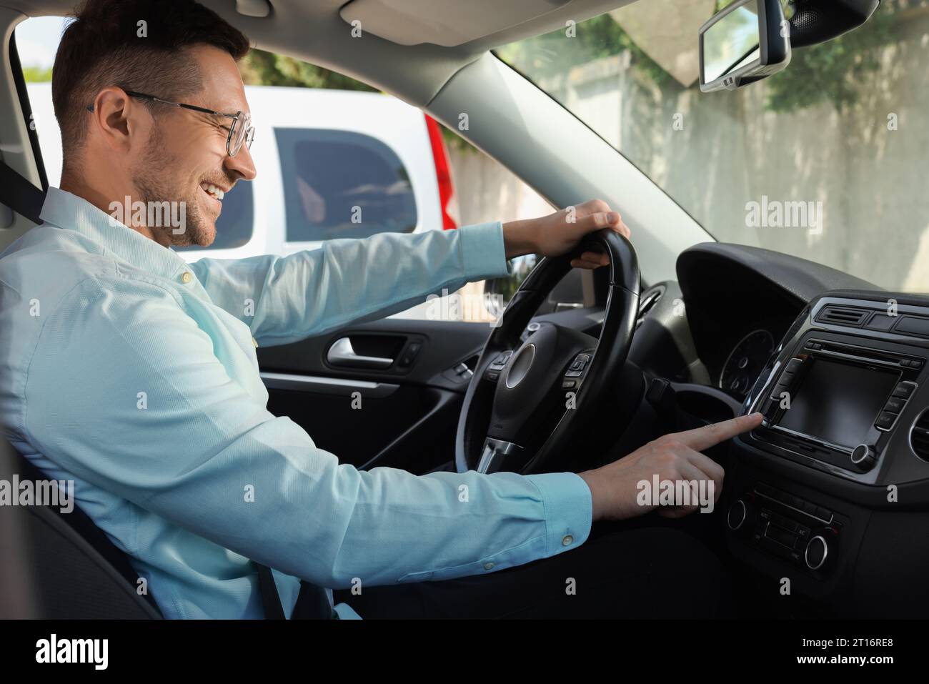 Listening to radio while driving. Handsome man turning volume button on ...