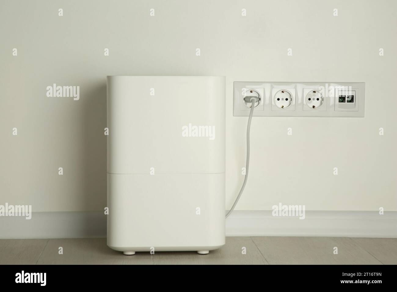 Modern air humidifier plugged into power socket on floor indoors Stock ...