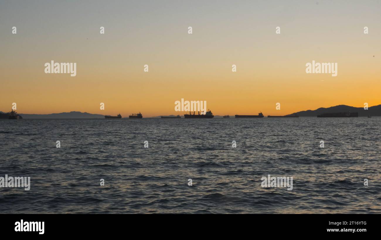 Silhouettes of large ships at the sea harbor at sunset. Tankers on the ...