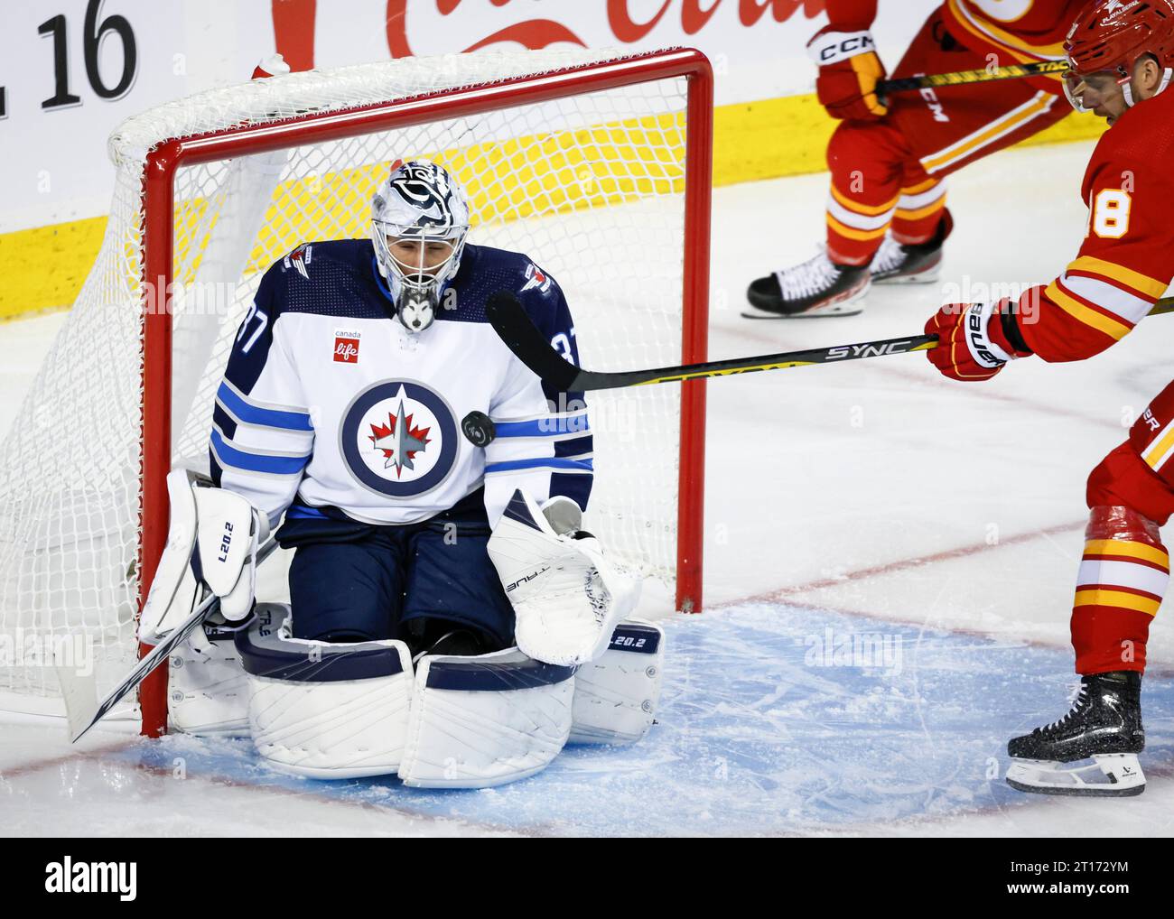 Winnipeg Jets goalie Connor Hellebuyck, left, gets hit by the stick of ...