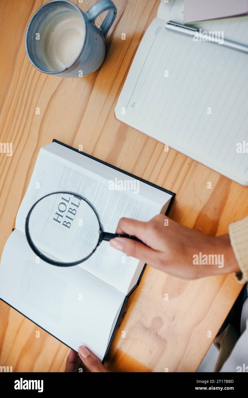 Bible, research and hands of person with magnifying glass to study ...