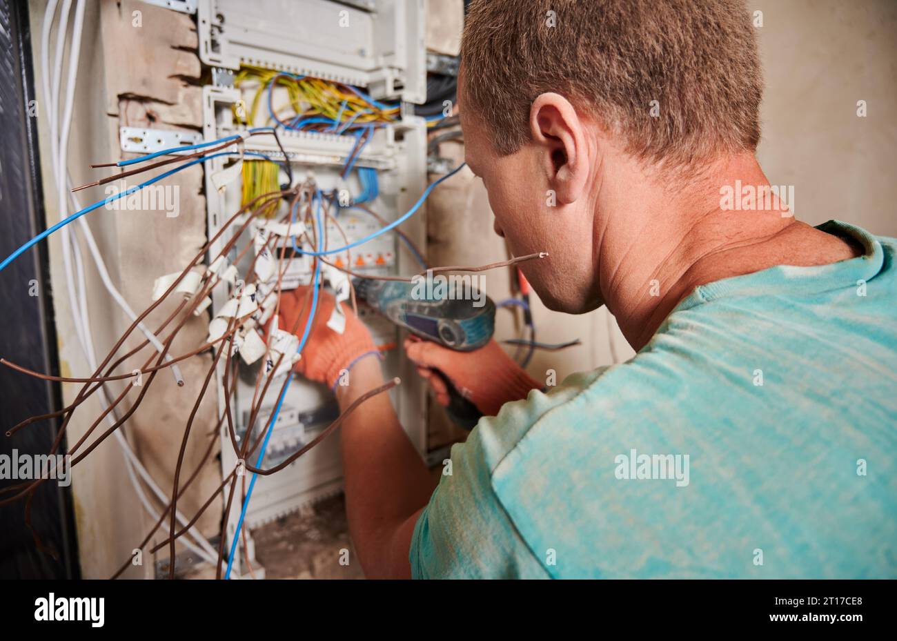 Back view of man in work gloves fixing electrical switchboard with ...