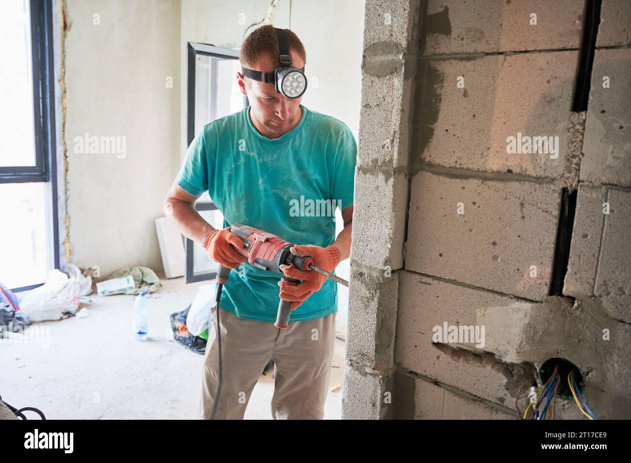 Male construction worker drilling brick wall with electric drill in ...