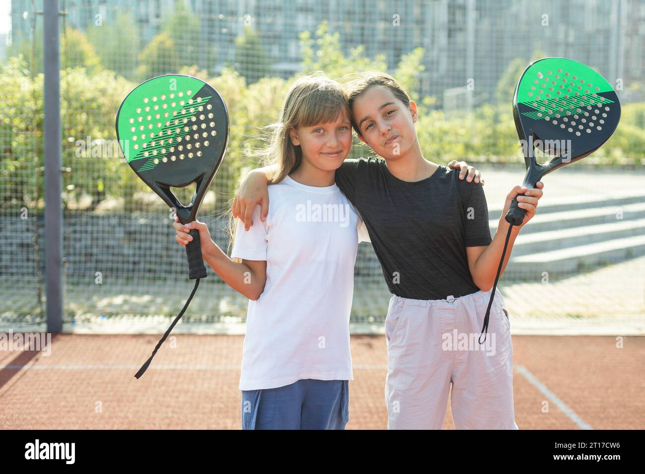 Teenage girls with racquets and balls standing in padel court, looking ...