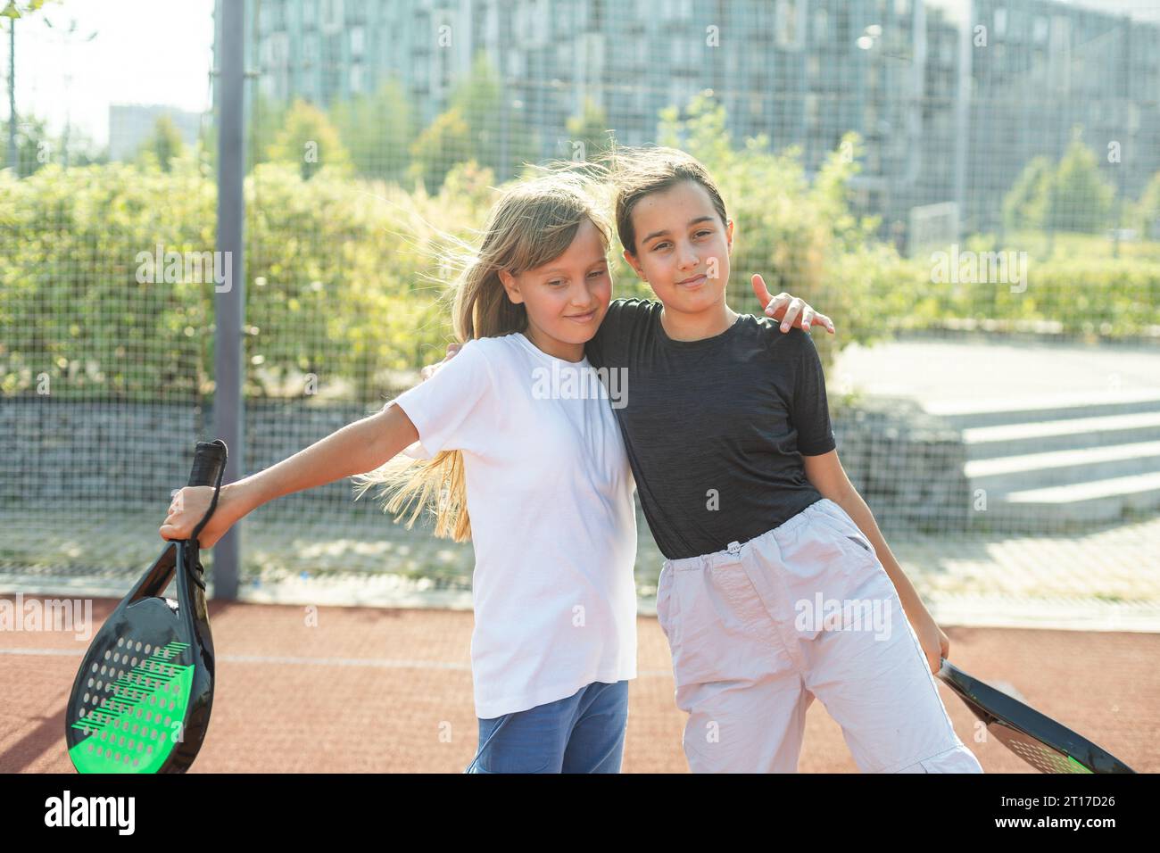 Teenage girls with racquets and balls standing in padel court, looking ...