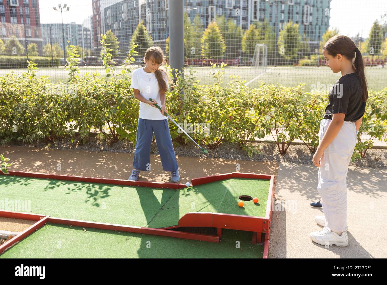 Cute school girl playing mini golf with family. Happy toddler child ...