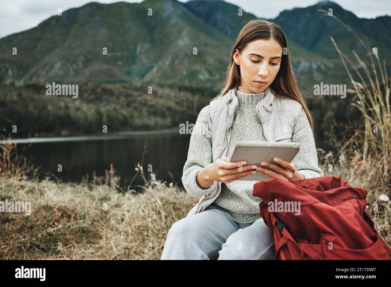 Tablet, backpack and woman hiking in nature on mountain for adventure ...
