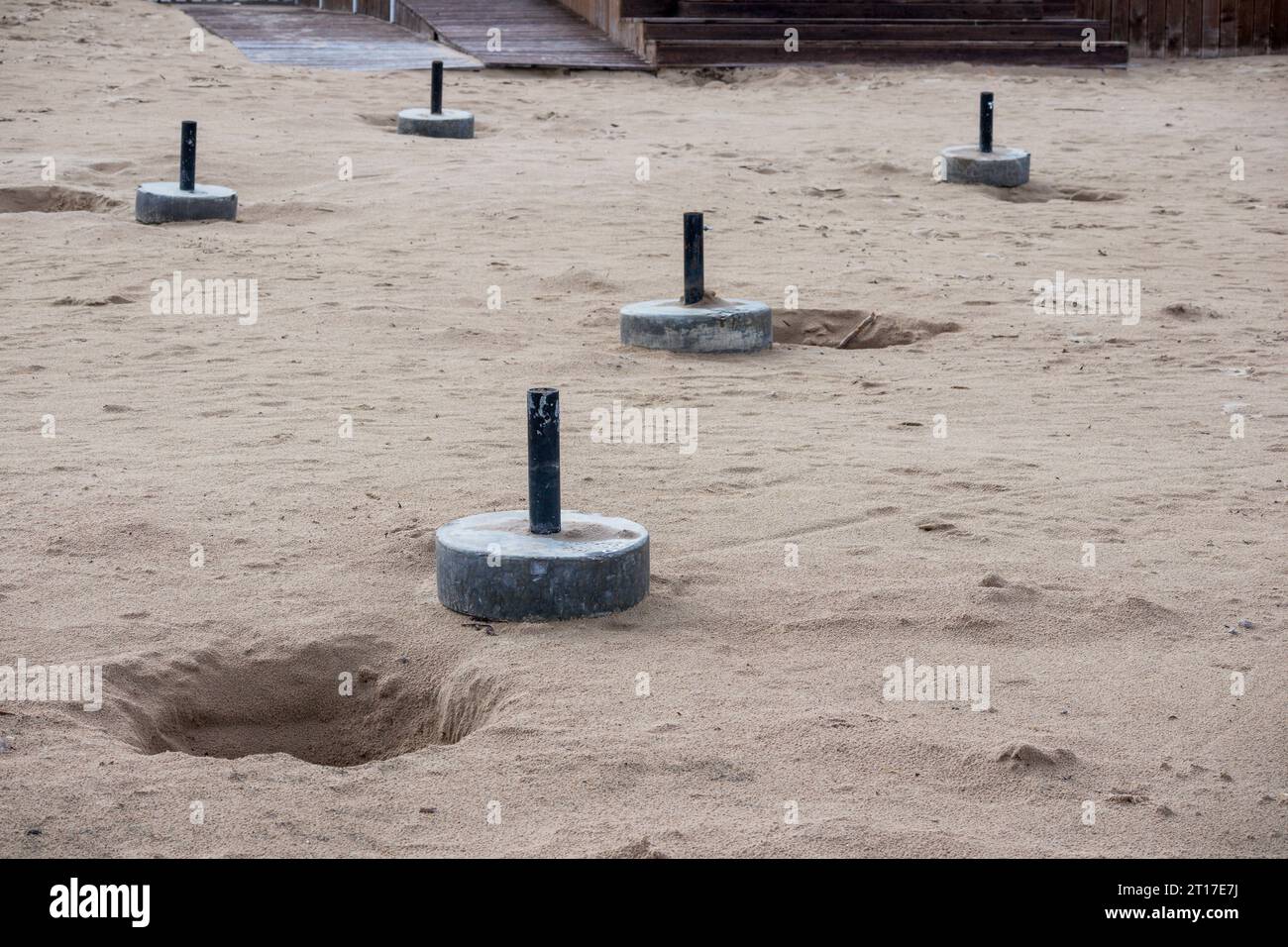 Concreted concrete posts with metal rod in sea sand Stock Photo - Alamy
