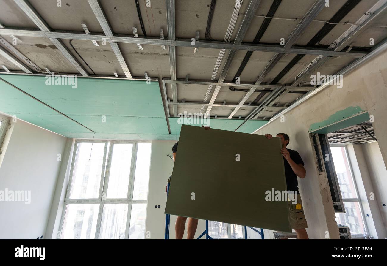 Workers fitting panel into frame of ceiling Stock Photo - Alamy