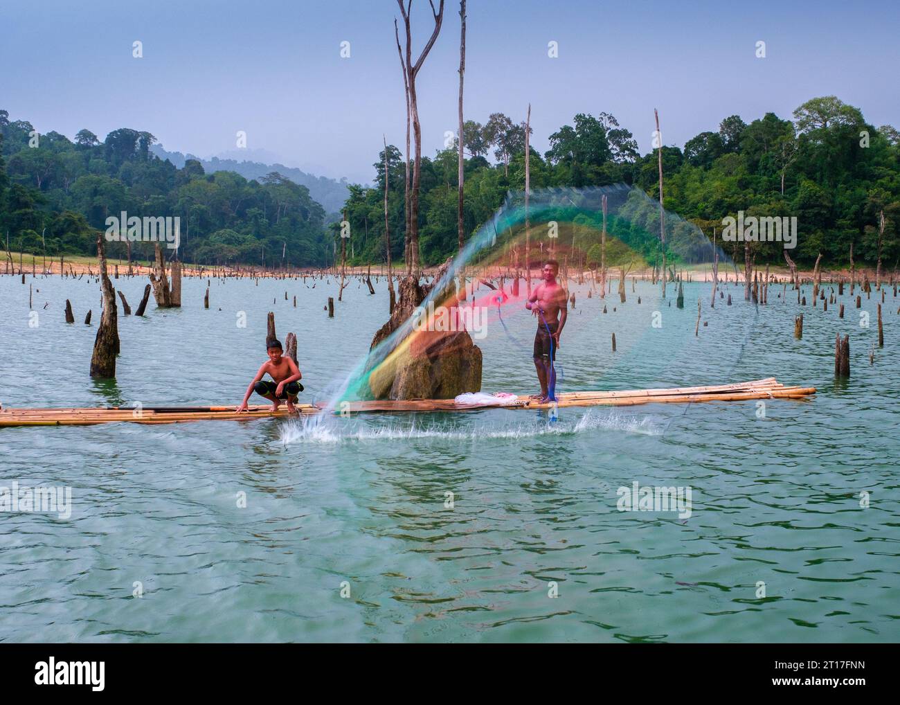 Indigenous men catching fish using net Stock Photo - Alamy
