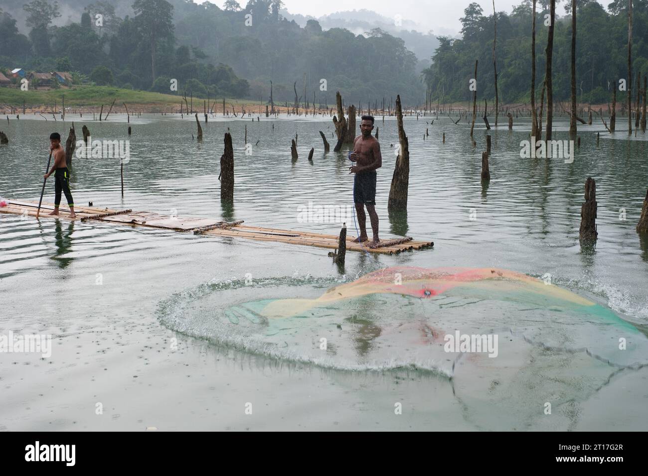 Indigenous men catching fish using net Stock Photo - Alamy