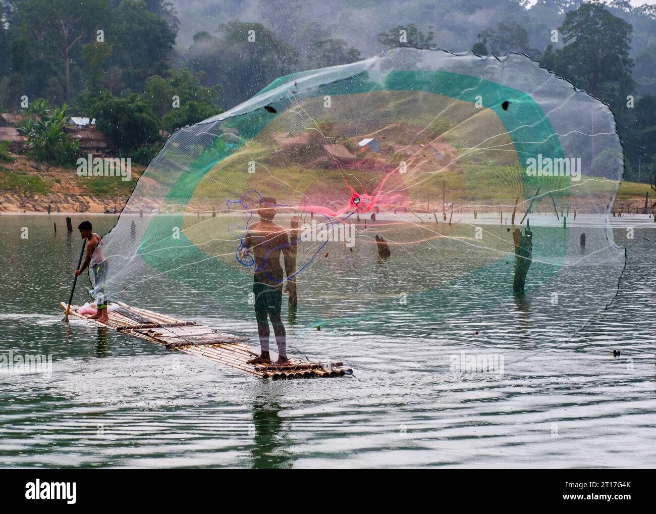 Indigenous men catching fish using net Stock Photo - Alamy