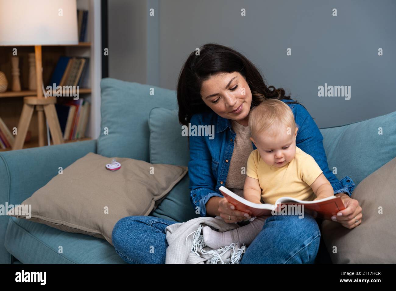 Mom reading a book with baby boy or girl at home. Early age children ...