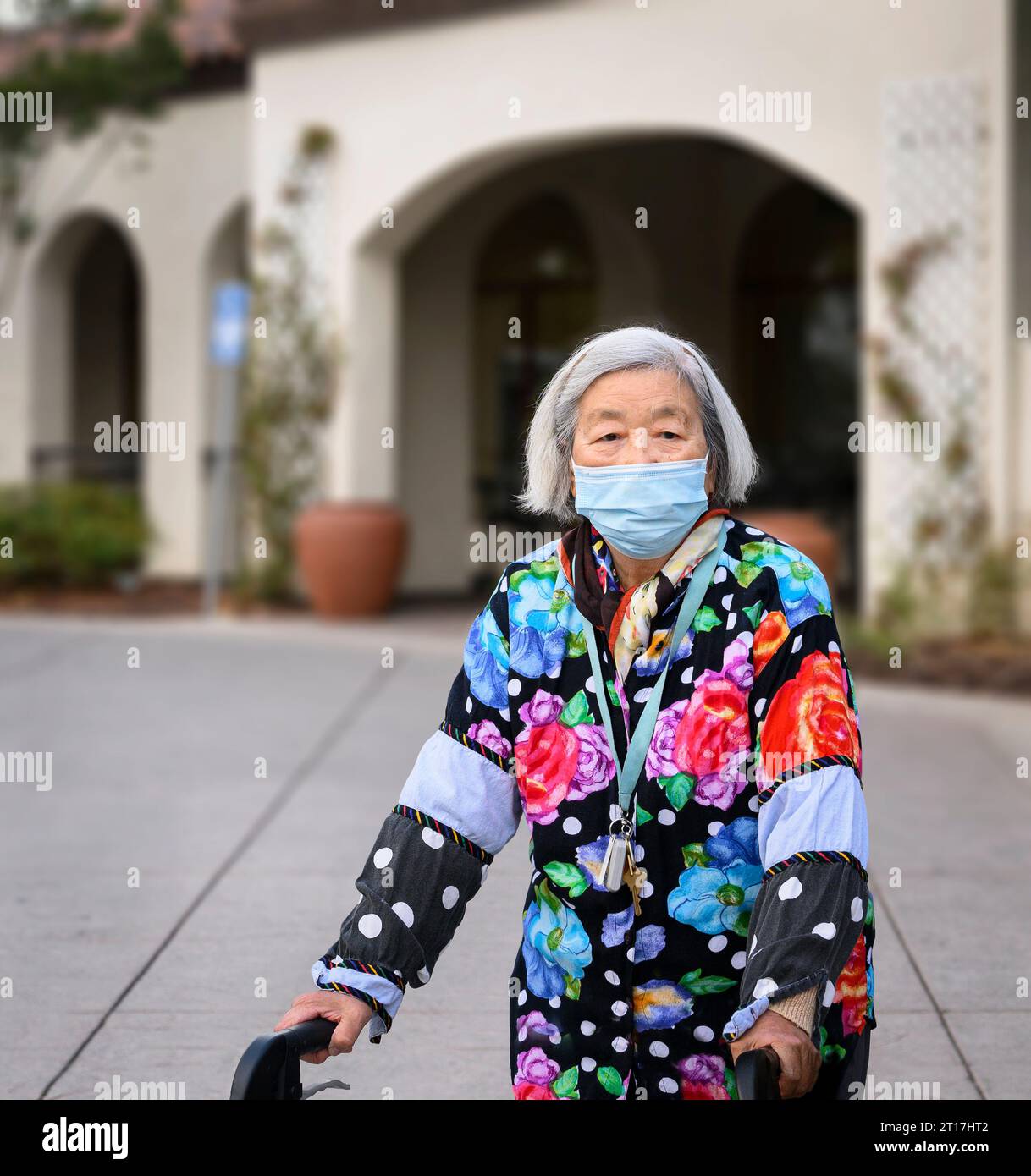 Senior woman with facemask walking outside the retirement village ...