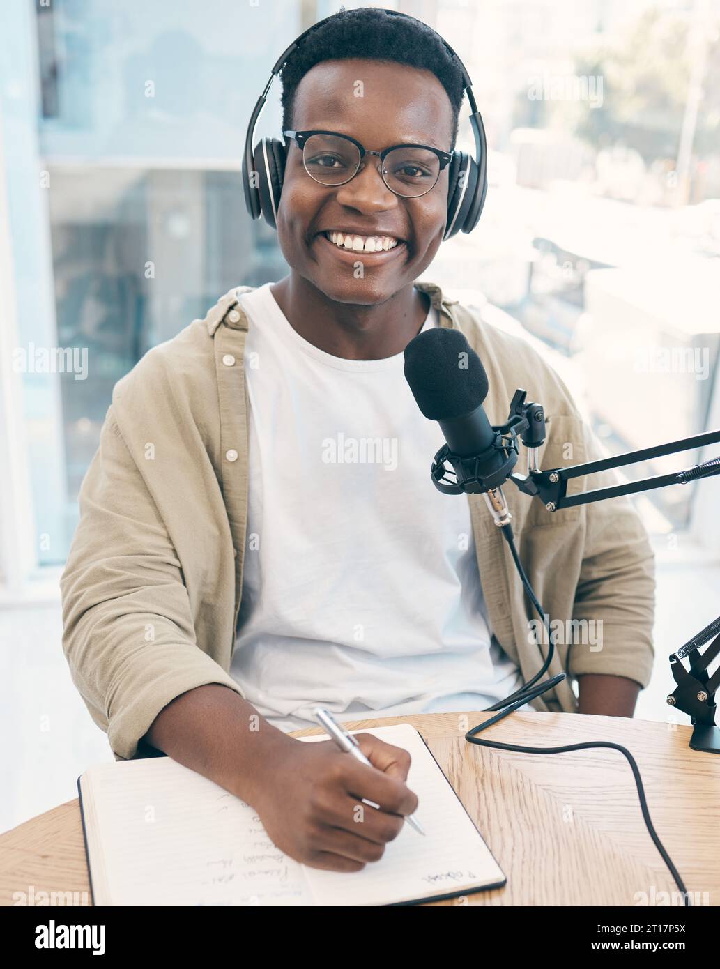 Portrait, podcast and black man with a notebook, microphone and smile ...