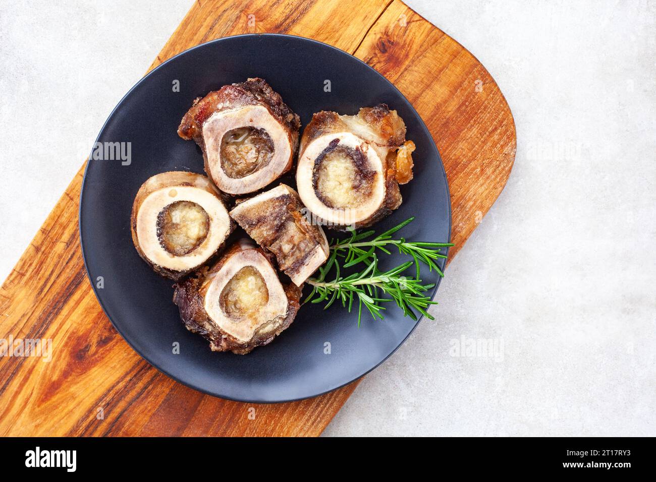 Roasted Marrow bones on a black plate with rosemary garnish Stock Photo ...