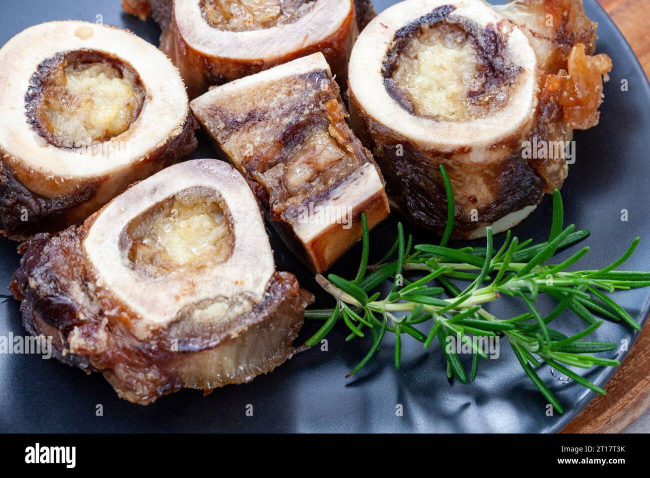 Roasted Marrow bones on a black plate with rosemary garnish Stock Photo ...