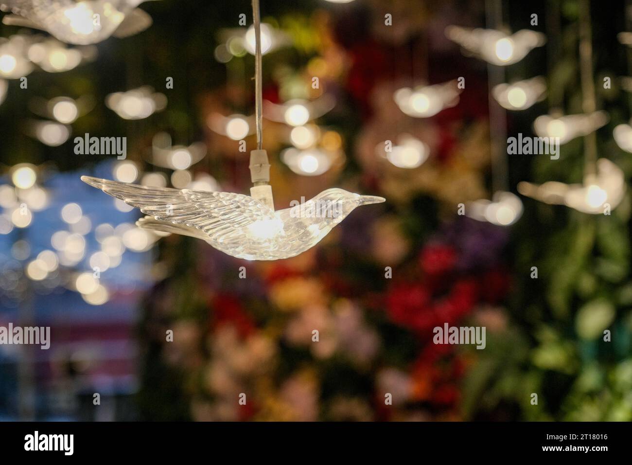 A dazzling glass bird, illuminated in festive brilliance, stands amidst ...