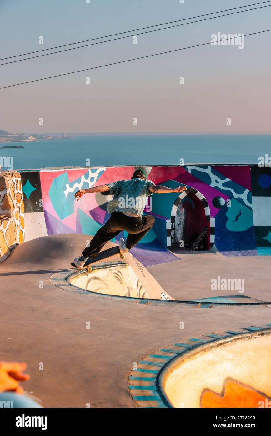 An active young man performing a skateboarding trick on a ramp in ...