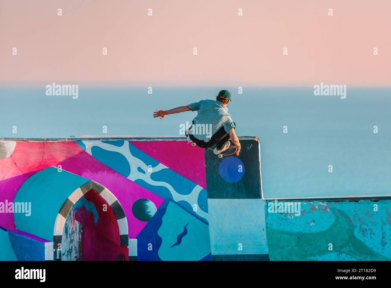 An active young man performing a skateboarding trick on a ramp in ...